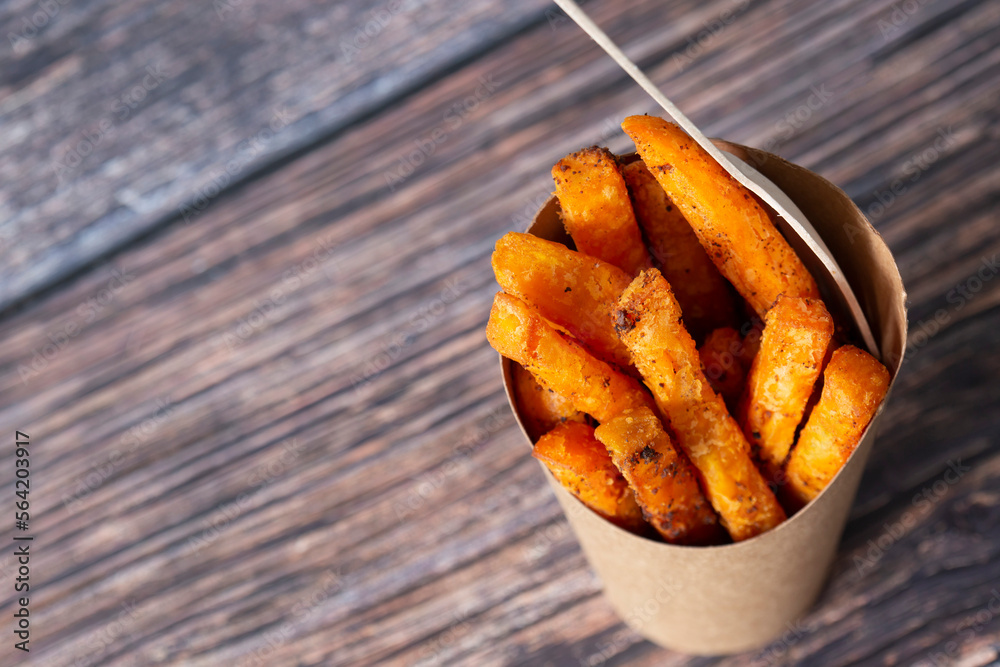 Sweet potato fries in a takeaway card container box with a wood fork ...