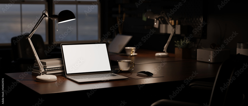Modern dark office at night with laptop mockup, light from table lamp ...