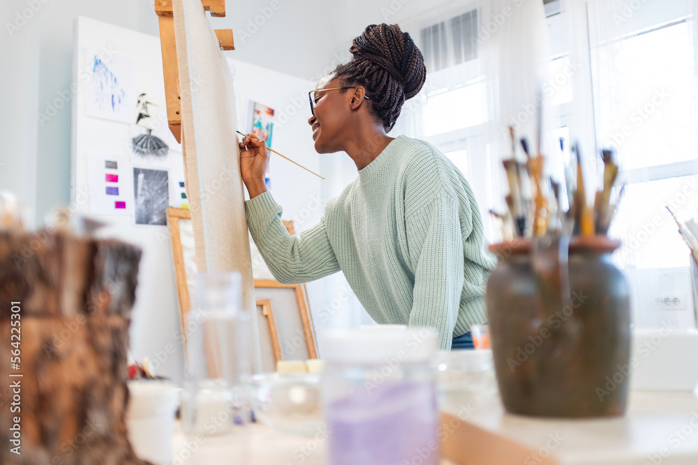 Young painter working in her atelier, she is working on a paint mounted ...