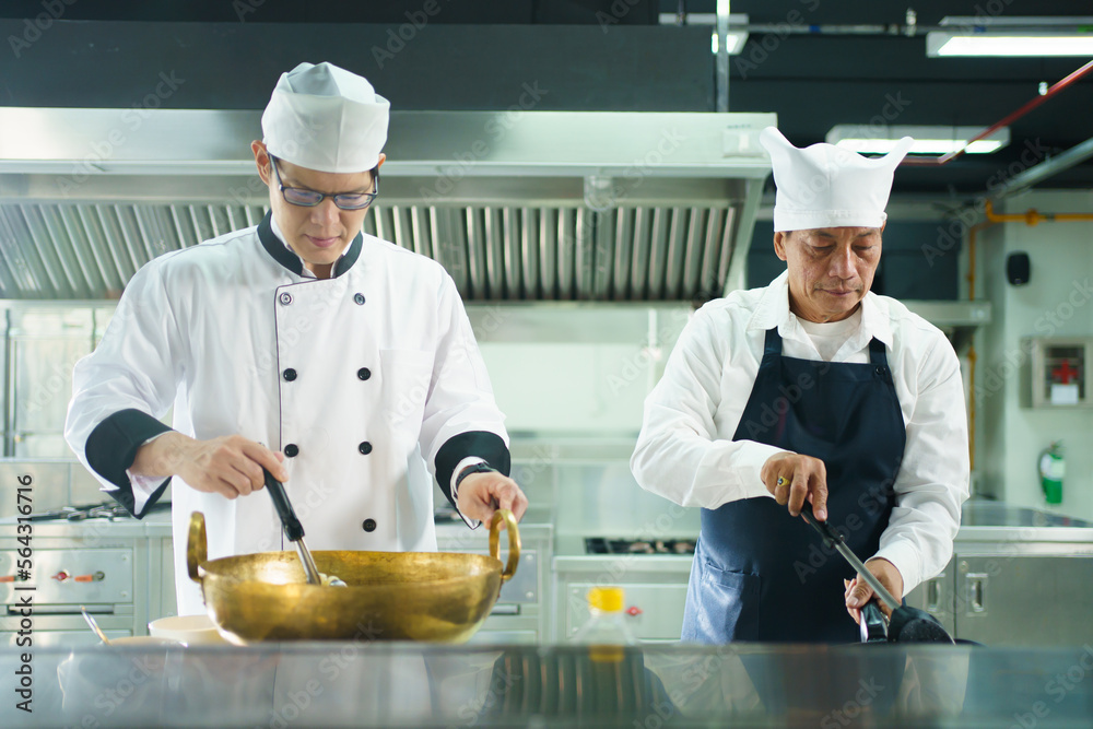 Happy Asian professional chef cooking in kitchen in Asian restaurant ...