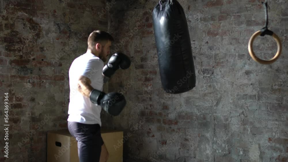 Intensive man in activewear punching during boxing workout in gym ...