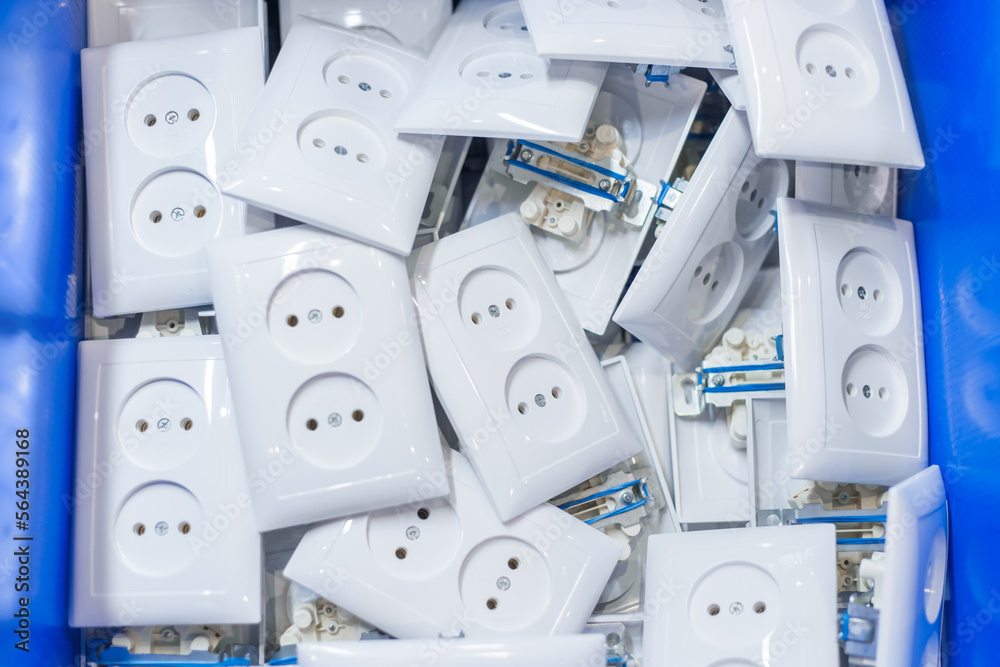 Many new white electric sockets, outlets in box at fabric, plant - top ...