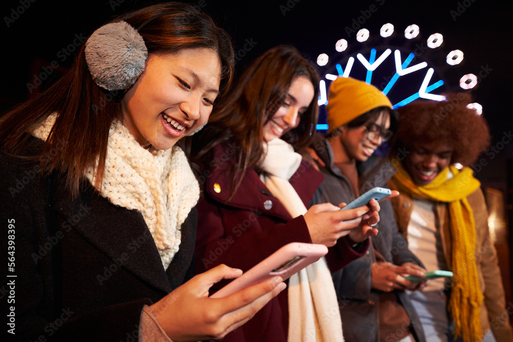 Foto de Group of friends using their cell phones at an amusement park ...