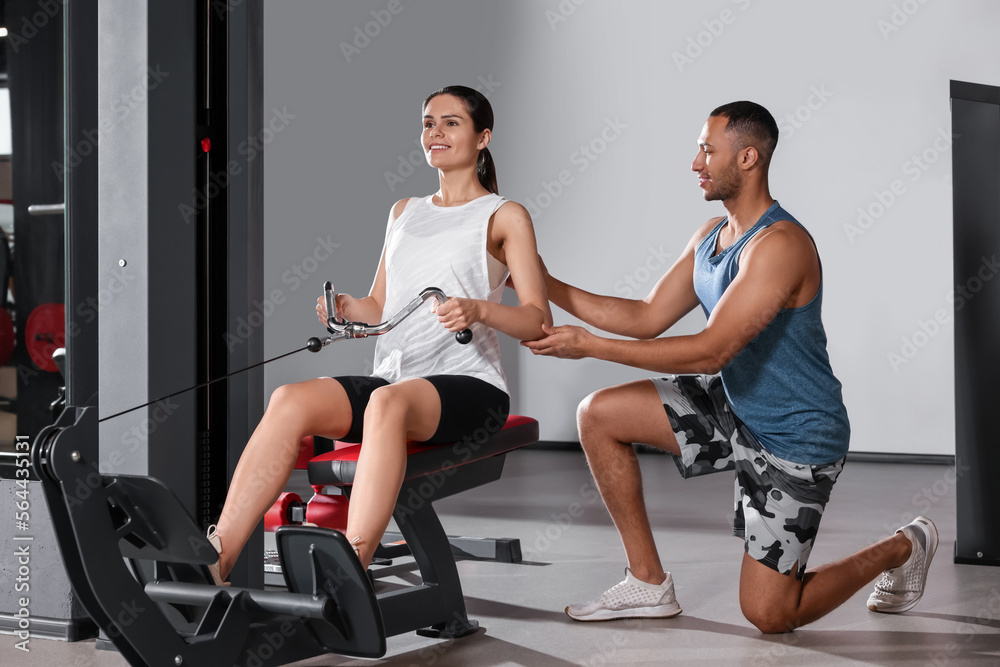 Trainer explaining woman how to do exercise properly in modern gym ...