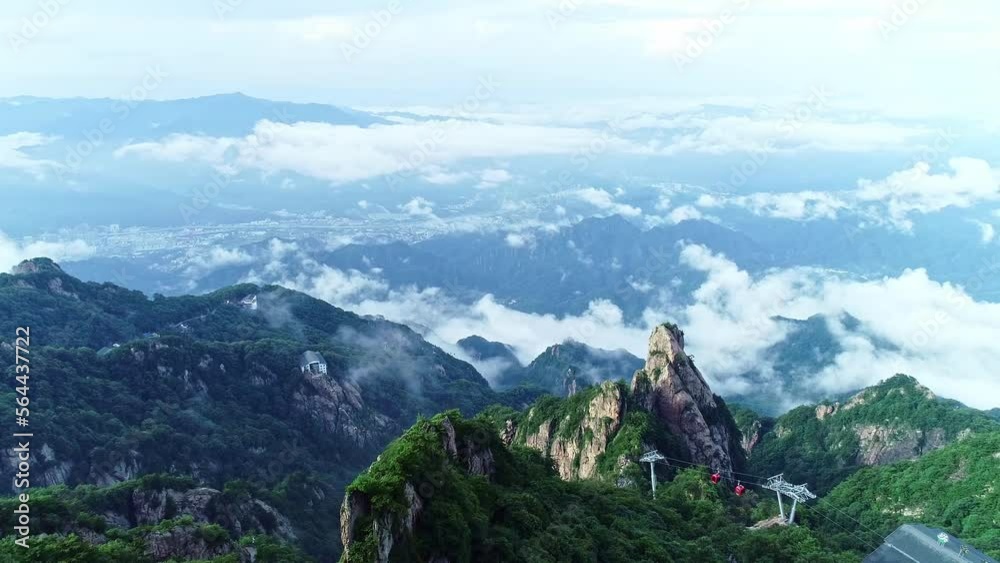 Aerial shot panning forward, mountains surrounded by clouds and fog ...