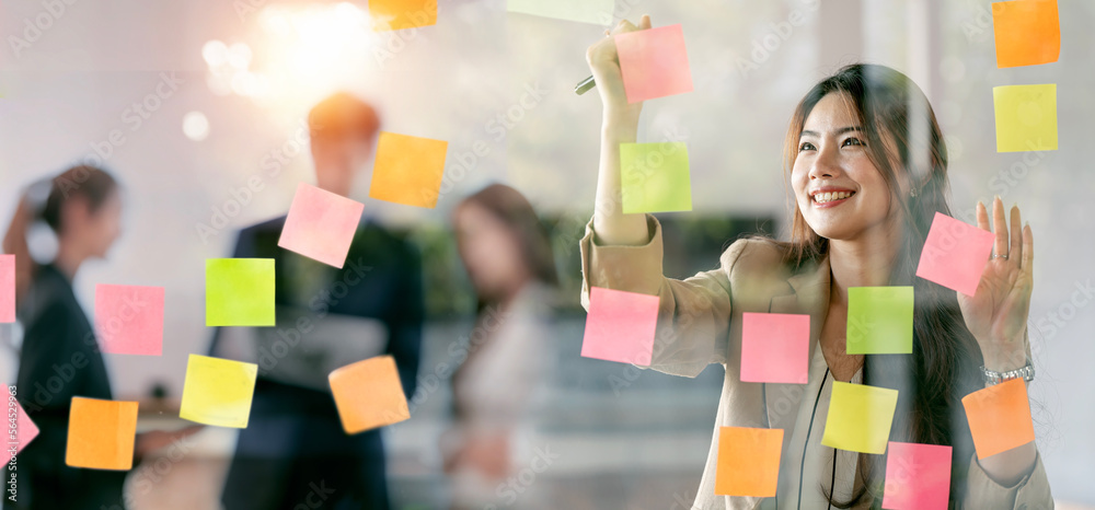 Young businesswoman creative team using post it notes in glass wall to ...