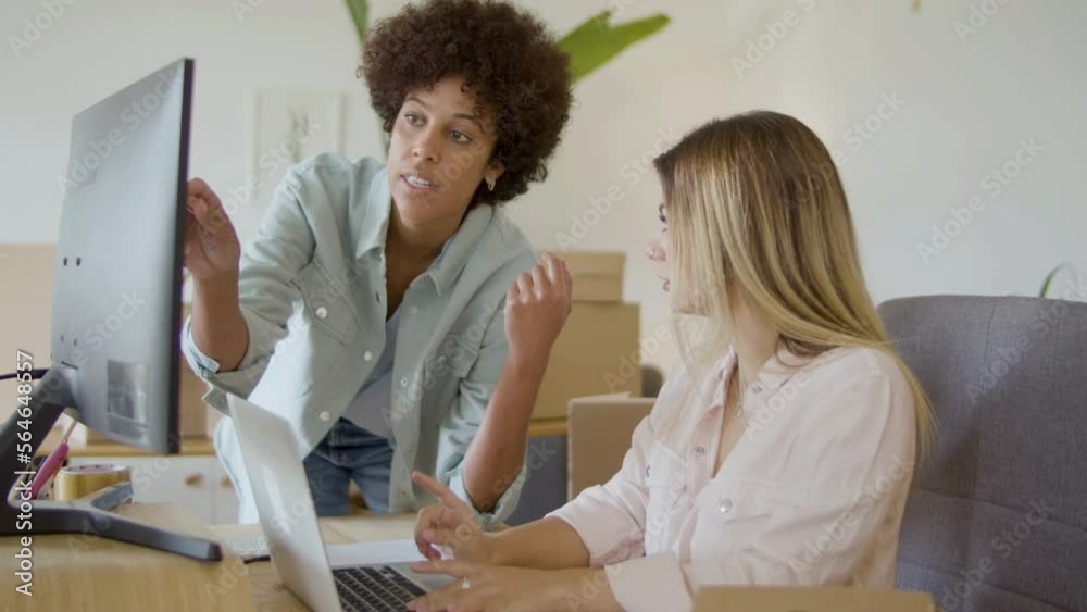 Two young women working together in office, checking and comparing data ...