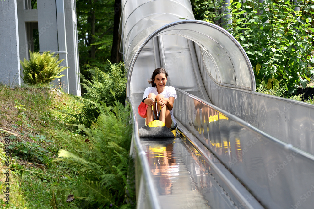 Foto de Smiling teenage girl sliding down on toboggan in the summer at ...