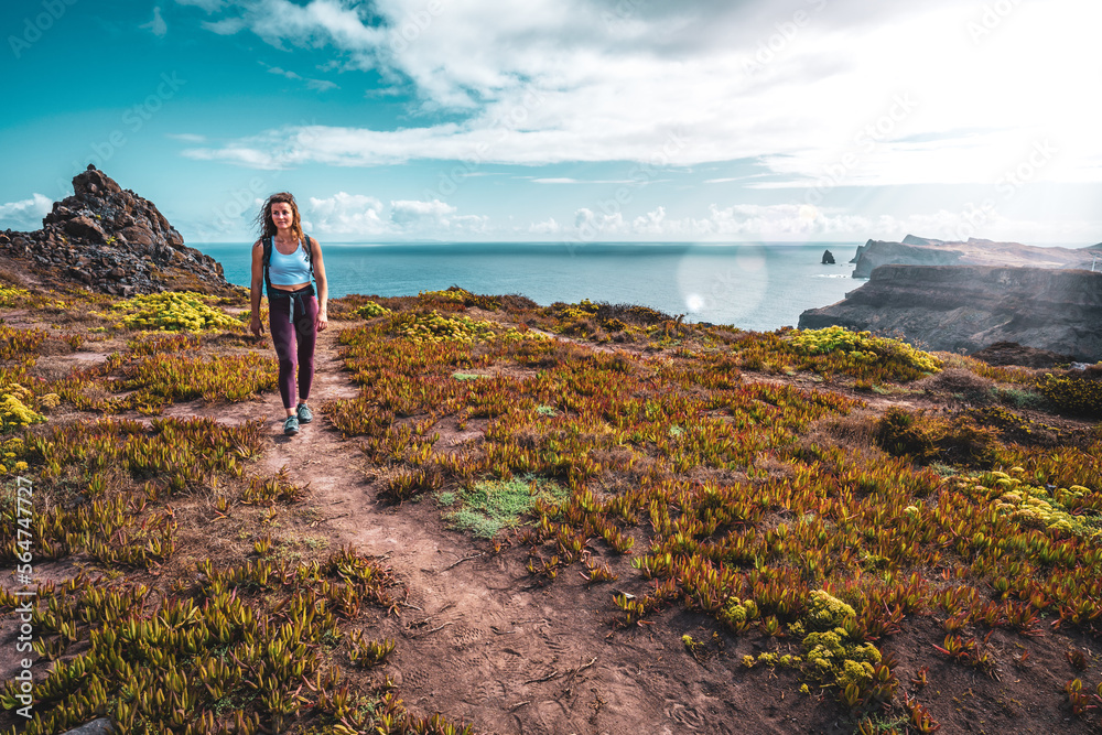 Backpacker woman enjoys hike along a steep cliff overlooking the sea ...