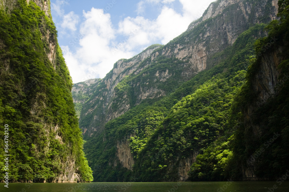 Lush limestone cliffs rise above the Grijalva River as it winds through ...