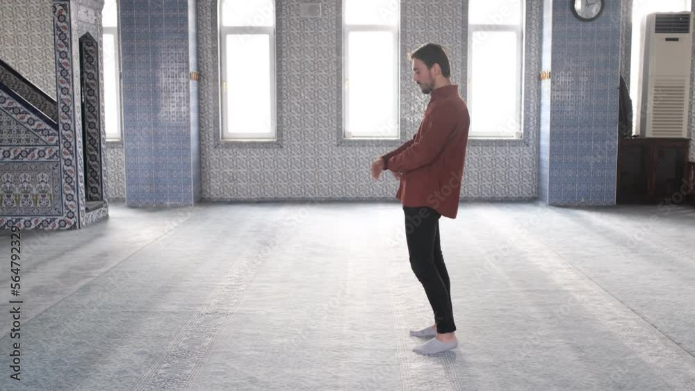 Side view of a bearded Muslim man standing to pray while prostrating ...
