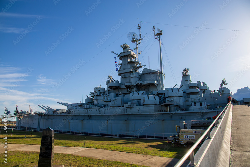 The USS Alabama Battleship with a bridge up to the ship and blue sky at ...