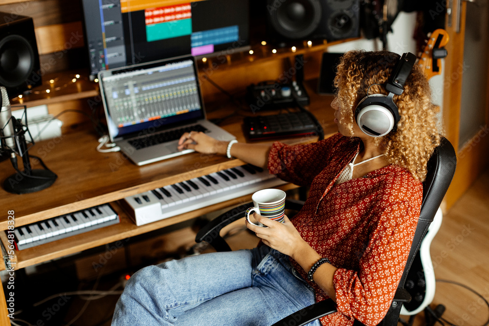Audio producer at home studio listens to music track and drinks coffee ...