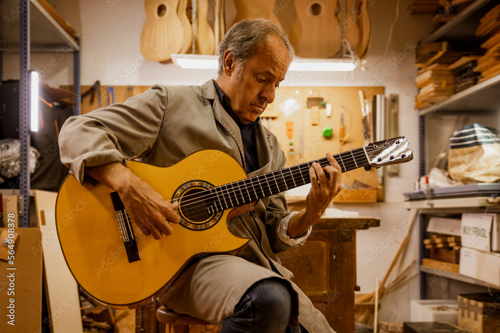 Luthier testing a finished custom classical guitar Stock Photo | Adobe ...