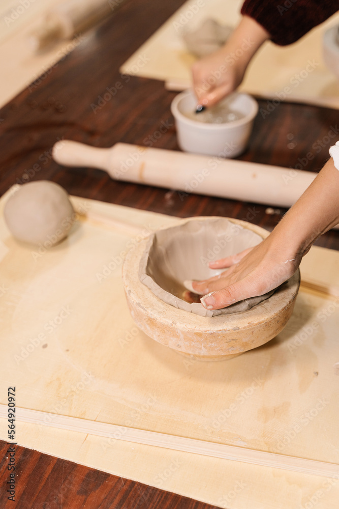Crop female masters forming clay pots in pottery Stock Photo | Adobe Stock