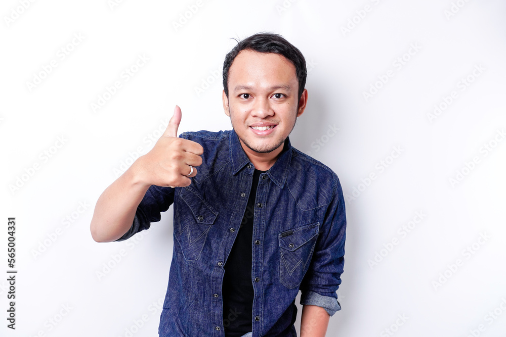 Excited Asian man wearing blue shirt gives thumbs up hand gesture of ...