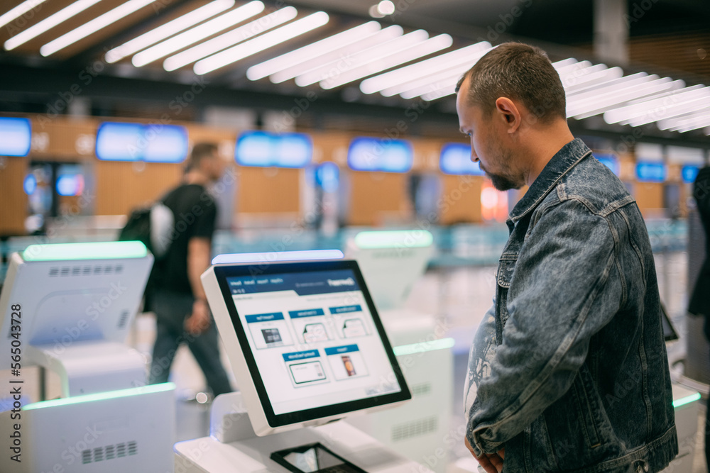 A male passenger at the electronic check-in desk in the departure area ...
