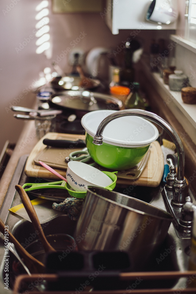 A counter and sink is filled to the brim with dirty dishes. The kitchen ...