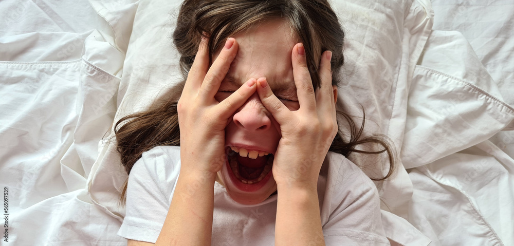 Foto de Portrait of little girl crying and screaming in horror on bed ...