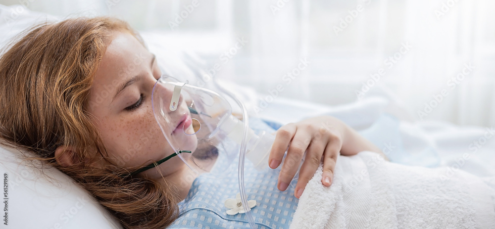 Portrait of little girl suffering from pneumonia lying in hospital bed with oxygen mask. Teenage ...