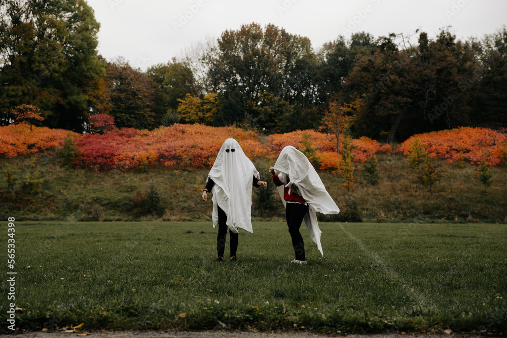 two friends dressed as ghosts are walking around the football stadium ...