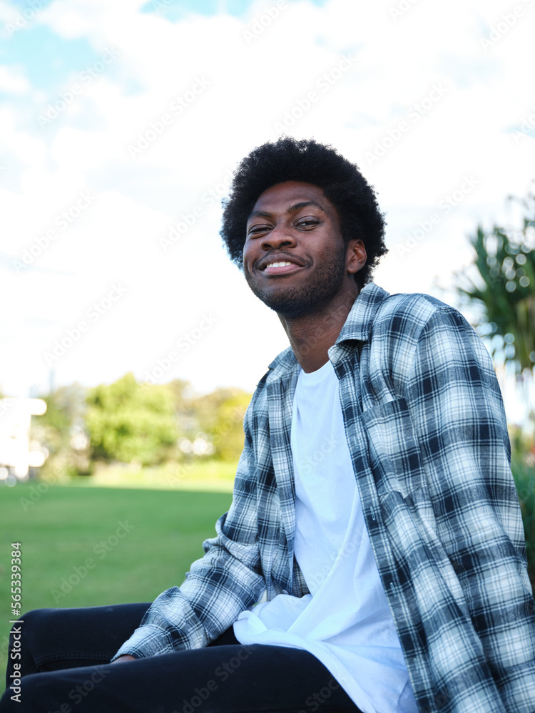 Smiling man sitting on a concrete park bench wearing a checkered polo ...