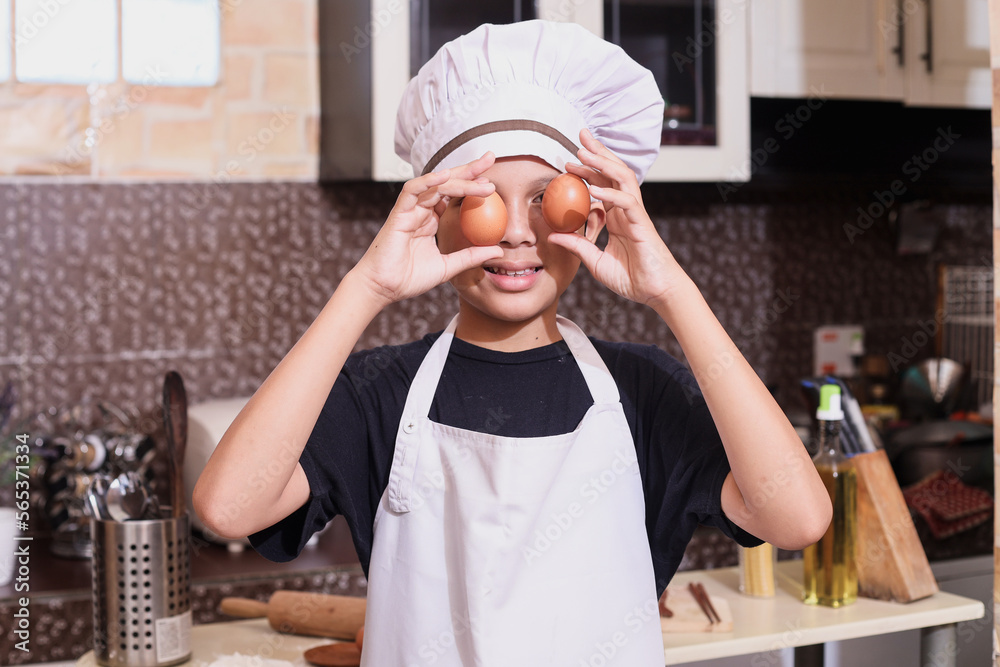 Cute boy using chef uniform putting eggs on eyes, feeling excited to ...