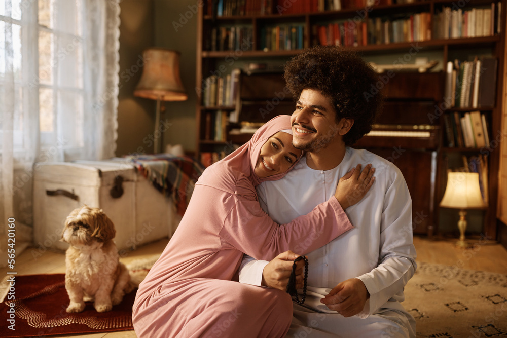 Happy Muslim man and his wife in traditional Muslim clothing embracing ...