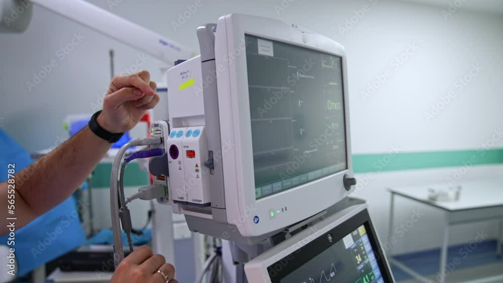 Male hands hold the screens of a lung ventilator in surgery room. Man ...
