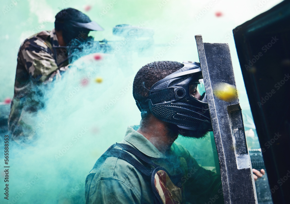 Paintball team, shooting together and war game with shield, mask or ...
