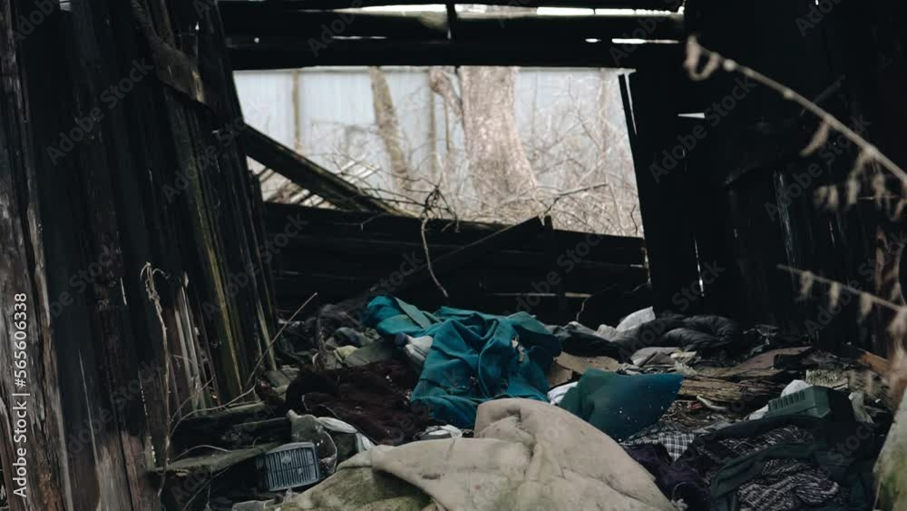 A broken and abandoned garage with sagging walls and a pile of garbage ...