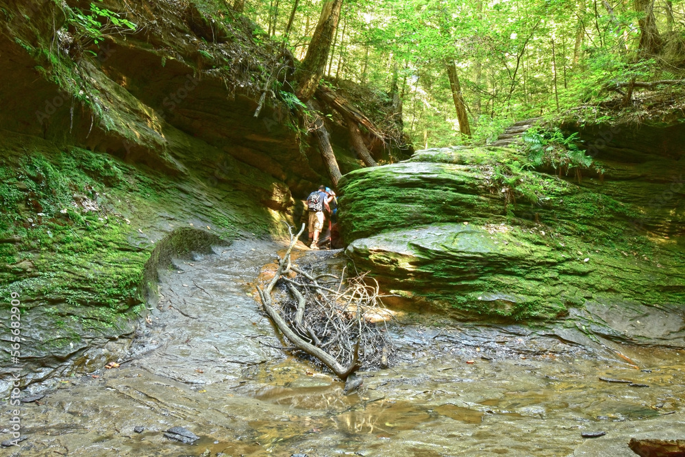 Hikers make their way through a narrow passage between layers of ...