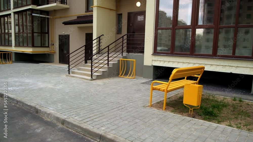 Bright yellow bench and litter bin at the entrance to multi-storied ...