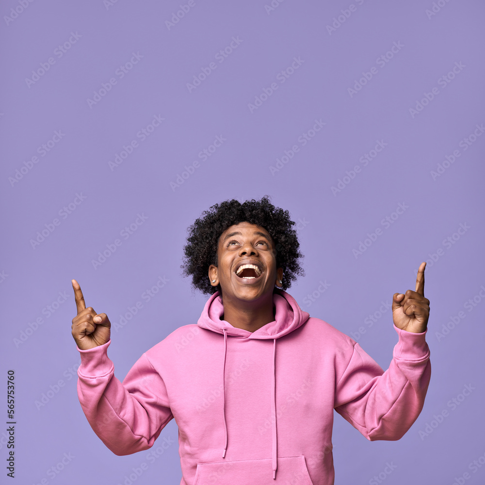 Happy surprised African American teen guy looking up presenting new promo offer. Amazed funny ...