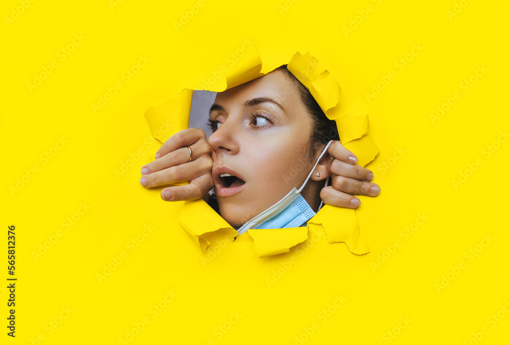 Surprised young woman with open mouth and protective medical mask looks ...