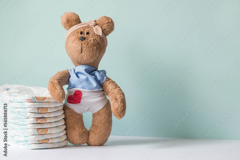 A stack of diapers and a stuffed teddy bear in diaper panties with a ...