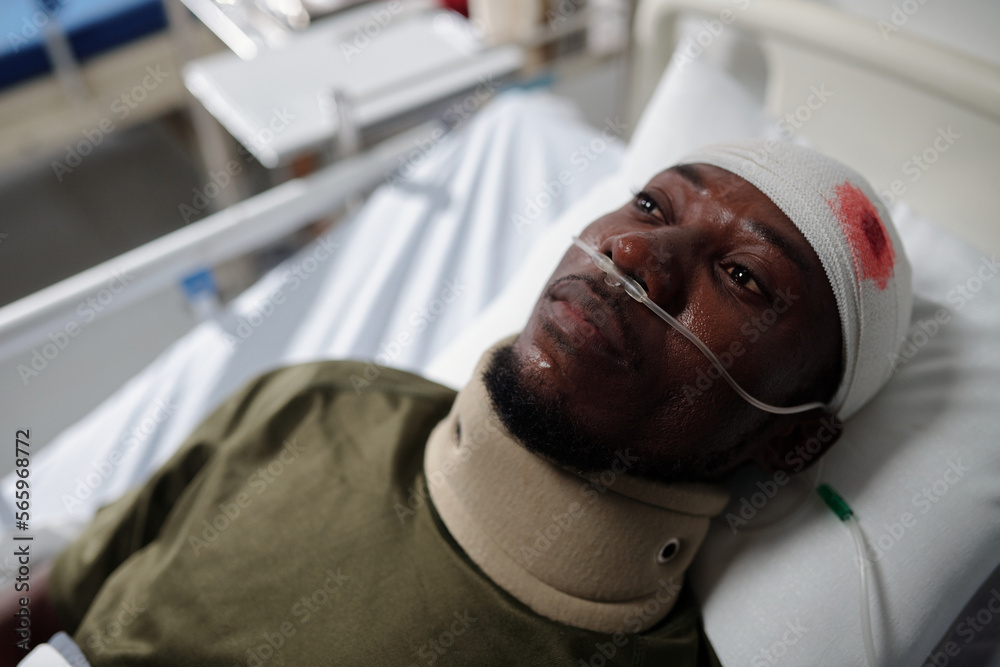 Sick military man with bleeding head injury lying on bed in hospital ...