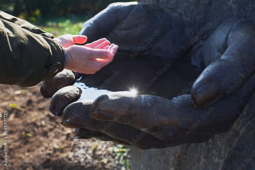 Small hands in big hands . Monument of human hands . Drinking water ...