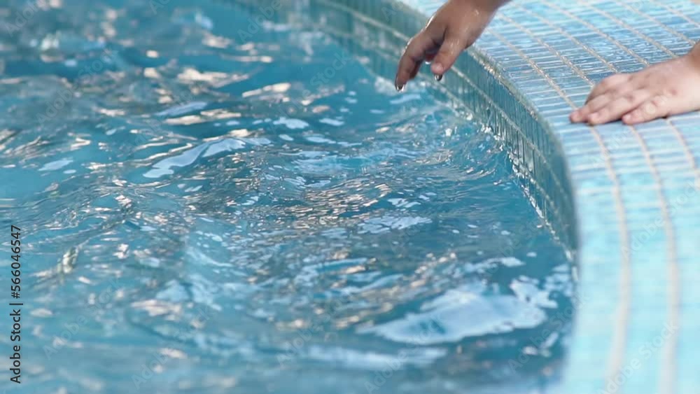 Toddler reaching to touch the water while playing near the swimming ...