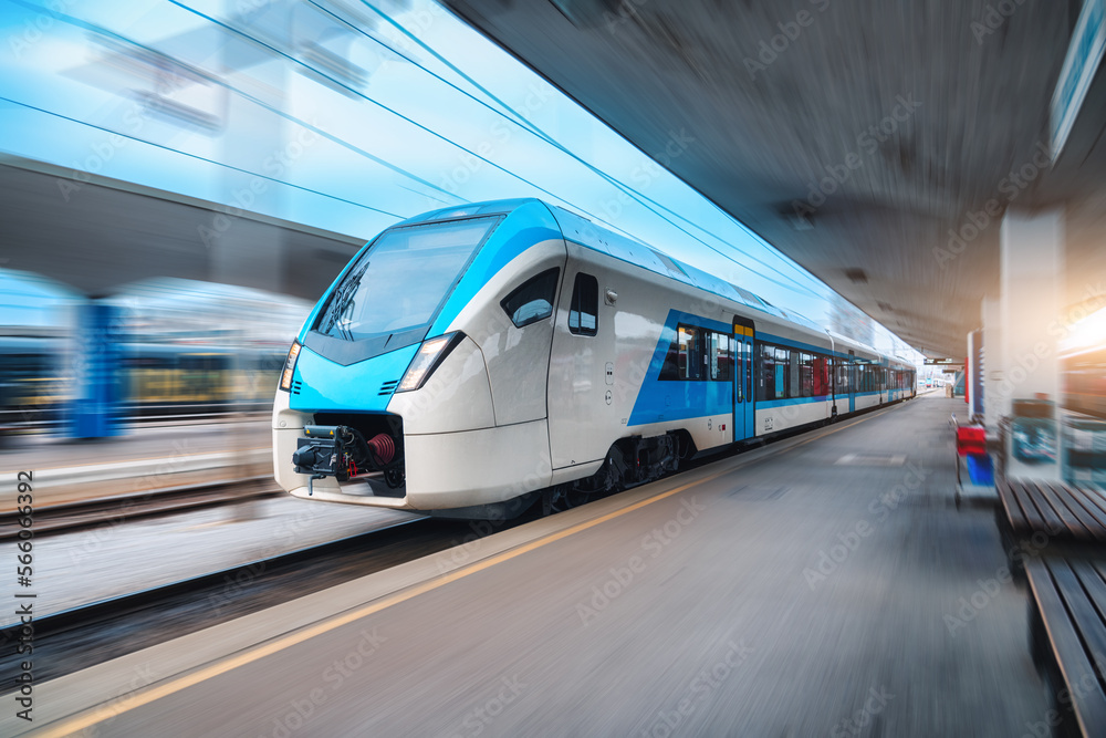 Blue high speed train in motion on the railway station at sunset. Fast ...