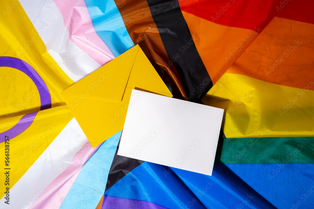 Empty paper blank on Rainbow LGBTQIA flag made from silk material. Mock ...
