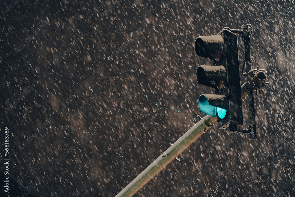 Green traffic light on a pole during a winter night with massive ...