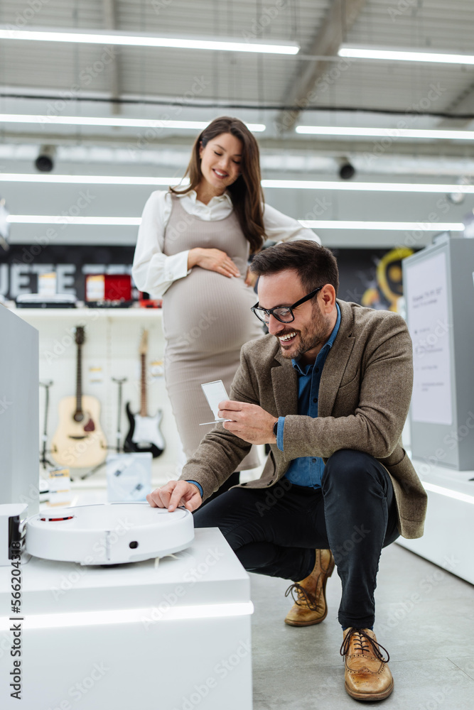 Beautiful and happy middle age couple buying consumer tech products in modern home tech store ...