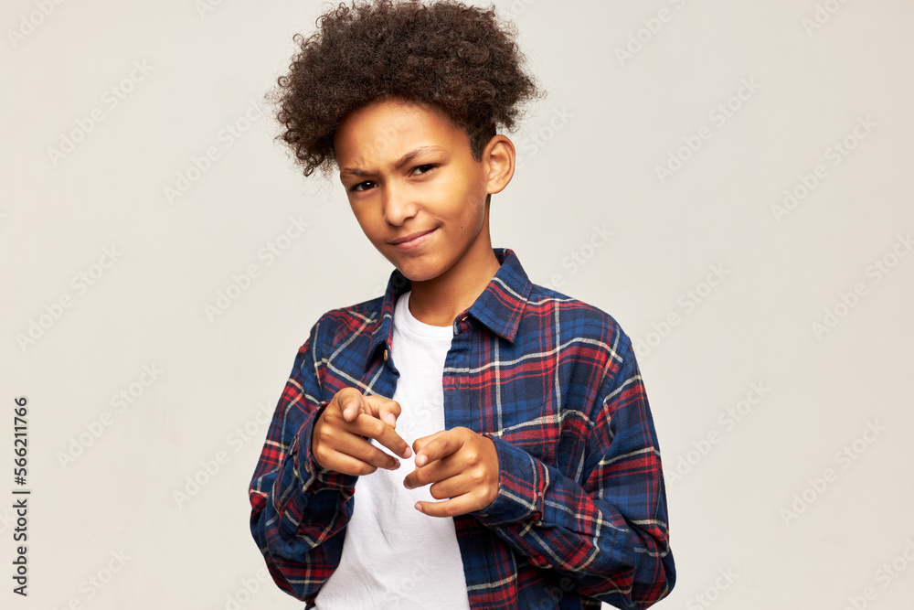 Skeptical frowning kid of african ethnicity pointing at camera with ...