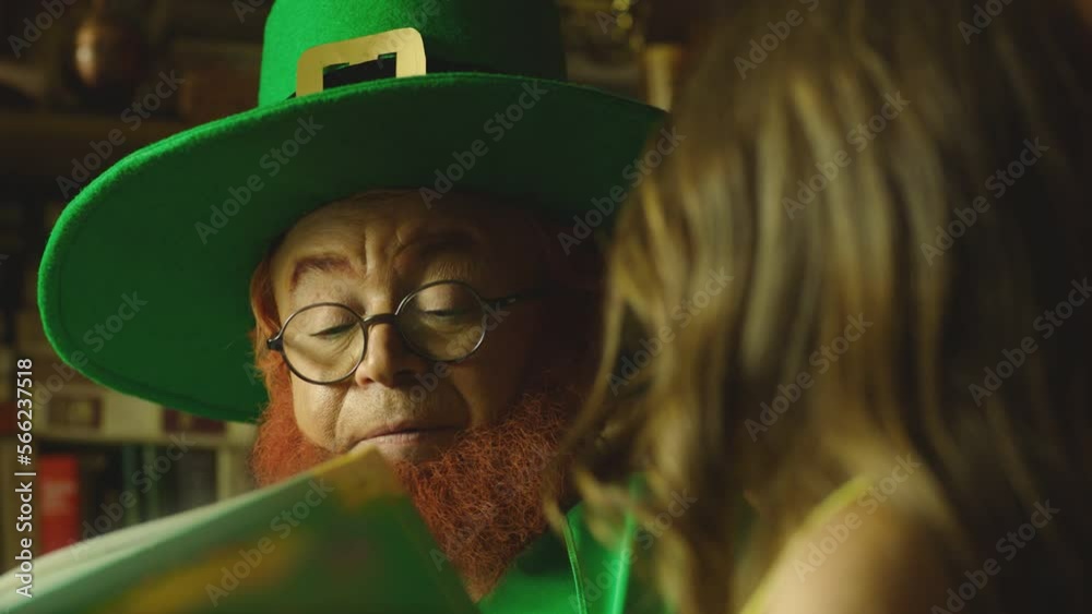 Old leprechaun is reading book , telling fairy tale story for little ...