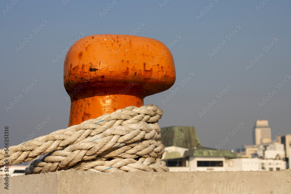 Bright orange mooring pole for mooring ships with a rope wrapped around ...