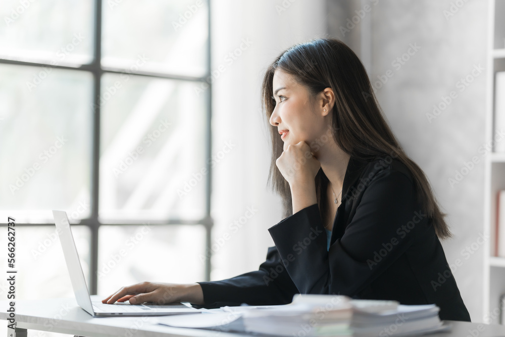 Beautiful Asian female bookkeeper doing online accounting with laptop ...