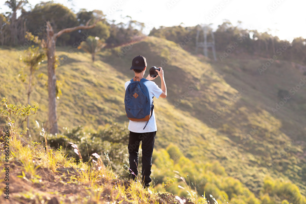 Videomaker standing on top of the mountain and filming the landscape ...