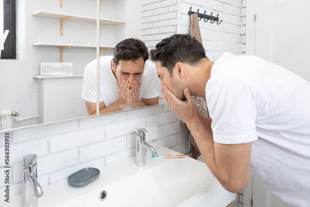 Handsome man washing his face in the bathroom. Morning routine and hygiene concept Stock Photo ...