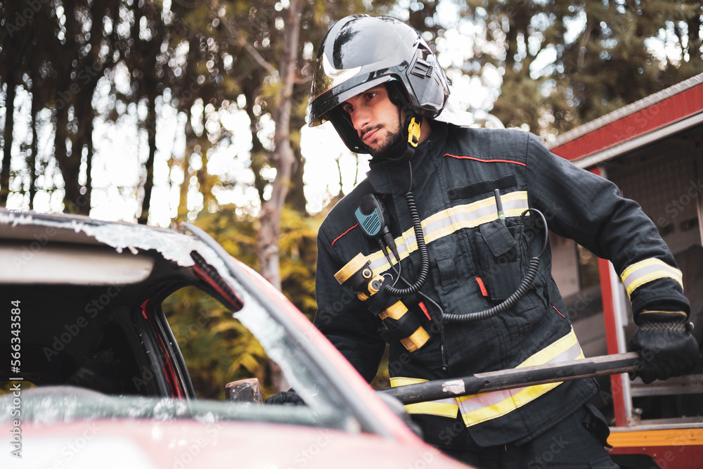 A young firefighter breaks the glass of a car that has suffered an ...